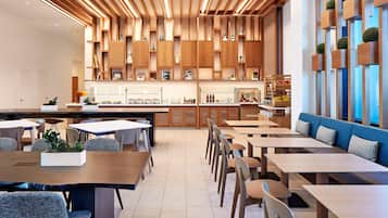 Restaurante moderno com painéis de madeira, uma ilha central e áreas de estar.