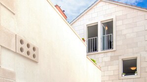 Uma escadaria de pedra leva a um edifício com fachada bege e uma janela no segundo andar, decorada com uma planta.