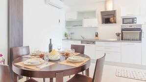 Uma cozinha moderna com armários brancos, forno embutido, micro-ondas e máquina de lavar louça.