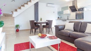 Uma sala de estar moderna com área de jantar, escada e cozinha.