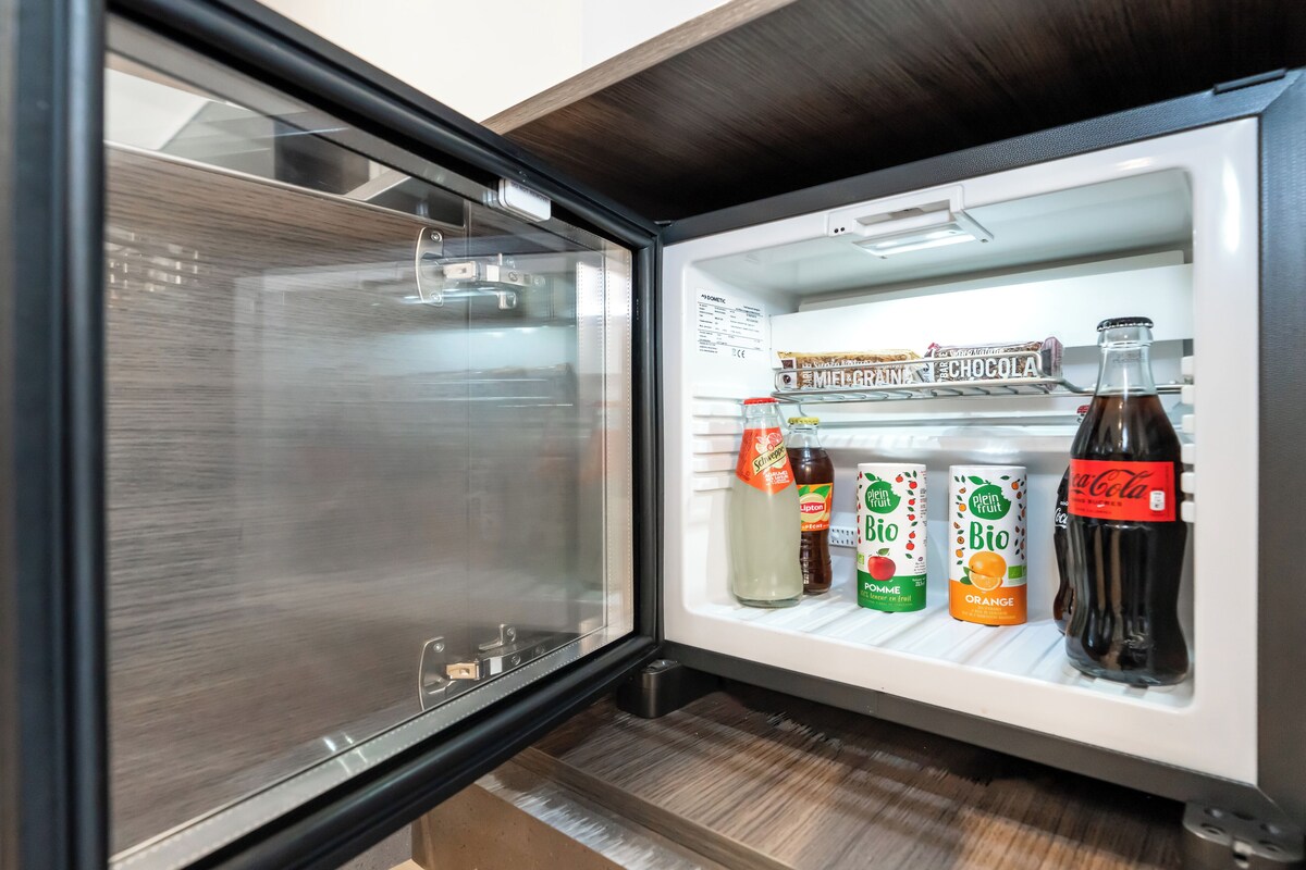 Geladeira aberta com prateleiras contendo diversas bebidas e uma garrafa de Coca-Cola.