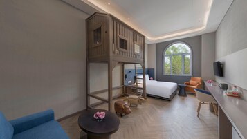 Quarto de hotel moderno com beliche, escrivaninha, cadeira, mesa redonda com um vaso e uma janela grande.
