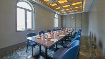 Uma sala de conferência com uma mesa comprida, cadeiras azuis e um design moderno no teto.