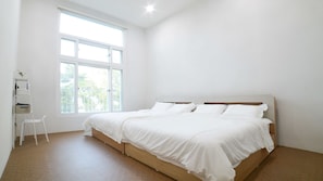 Quarto com uma janela grande, cama com roupa de cama branca, cadeira branca e estante branca.