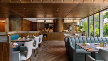 Um restaurante moderno com painéis de madeira, uma área de bar central e diferentes disposições de assentos.