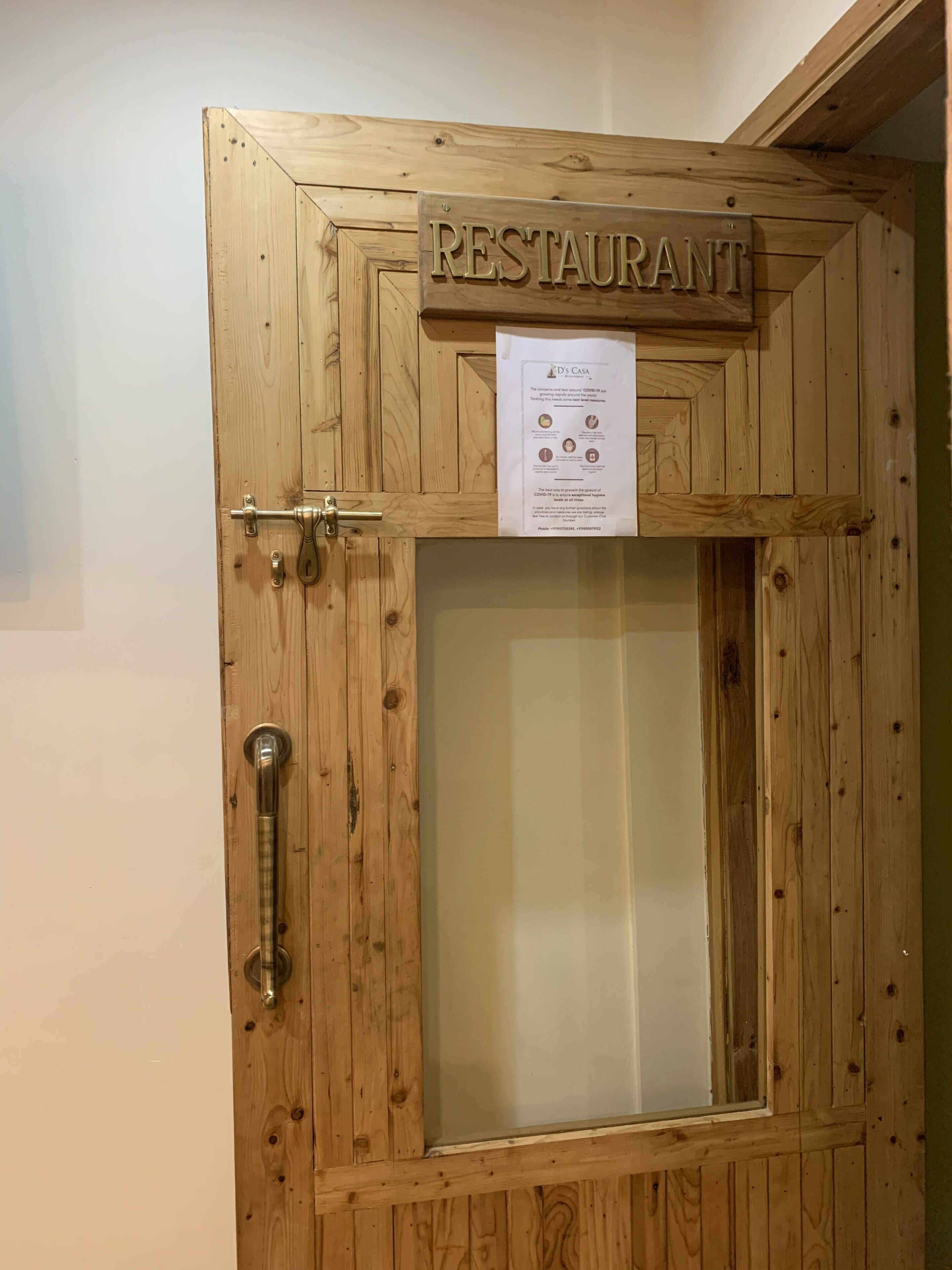 Uma porta de madeira com um painel de vidro e uma placa com a palavra 'RESTAURANT' em cima.