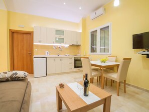 Uma cozinha compacta com área de refeições, um sofá e uma televisão fixada na parede.