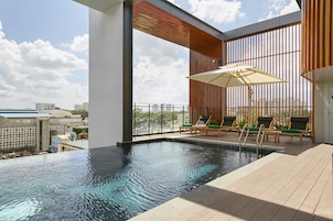 Piscina interior com vista para a paisagem urbana, deck de madeira e espreguiçadeiras.