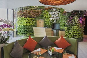 Um interior moderno com um sofá verde, uma mesa de jantar e uma parede de jardim vertical.
