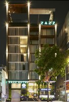 Um edifício de vários andares com uma placa na entrada que diz 'Zazz Hotel'.