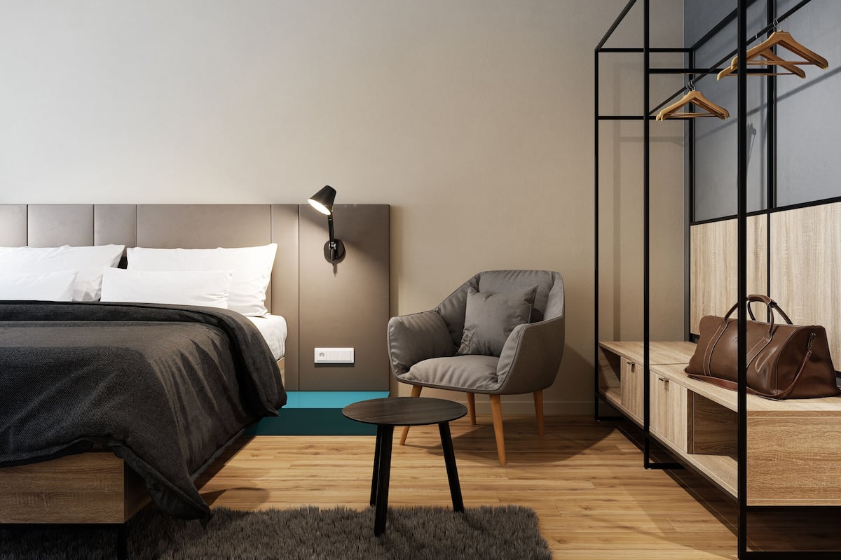 Quarto moderno com cama, mesa de cabeceira, cadeira e guarda-roupa com espaço para pendurar roupas.