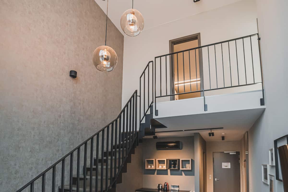 Um apartamento moderno com escada que dá para um loft, sala de estar com sofá e mesa de centro, e cozinha.