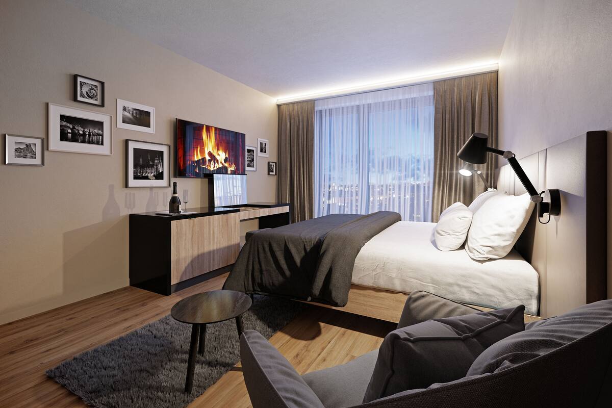 Quarto de hotel moderno com cama, escrivaninha, sofá e vista para a cidade.