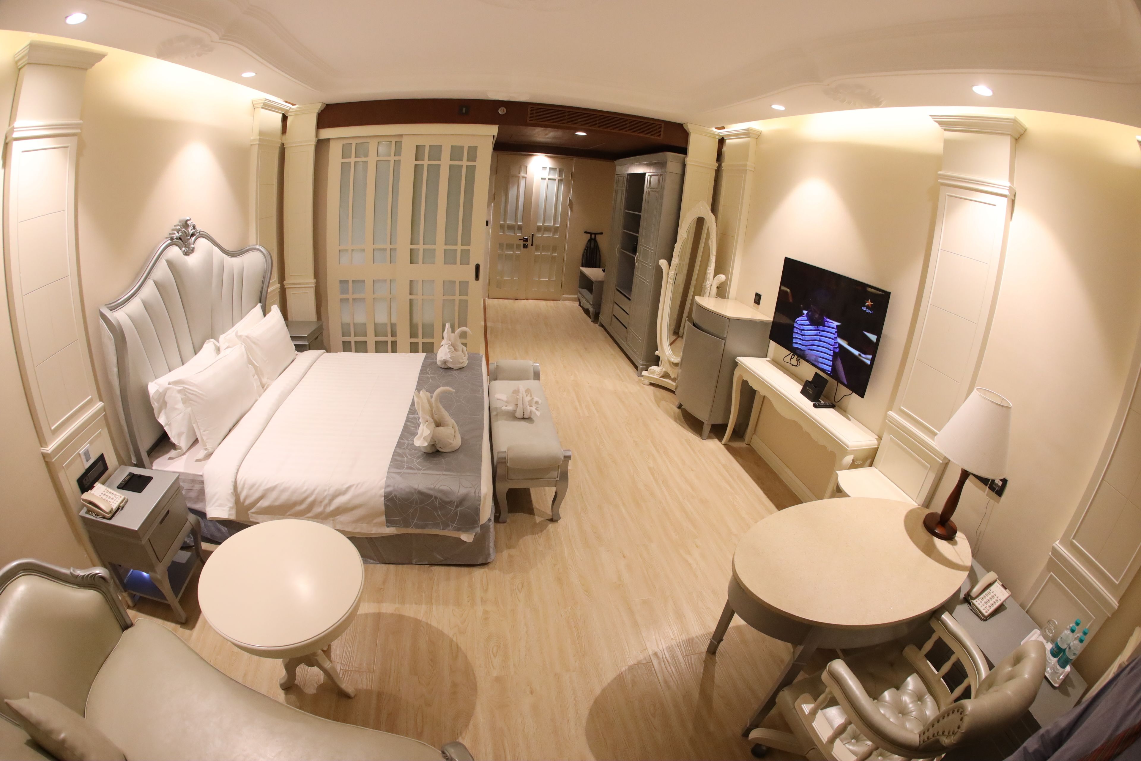 Quarto de hotel com uma cama grande, televisão, escrivaninha e uma cadeira.