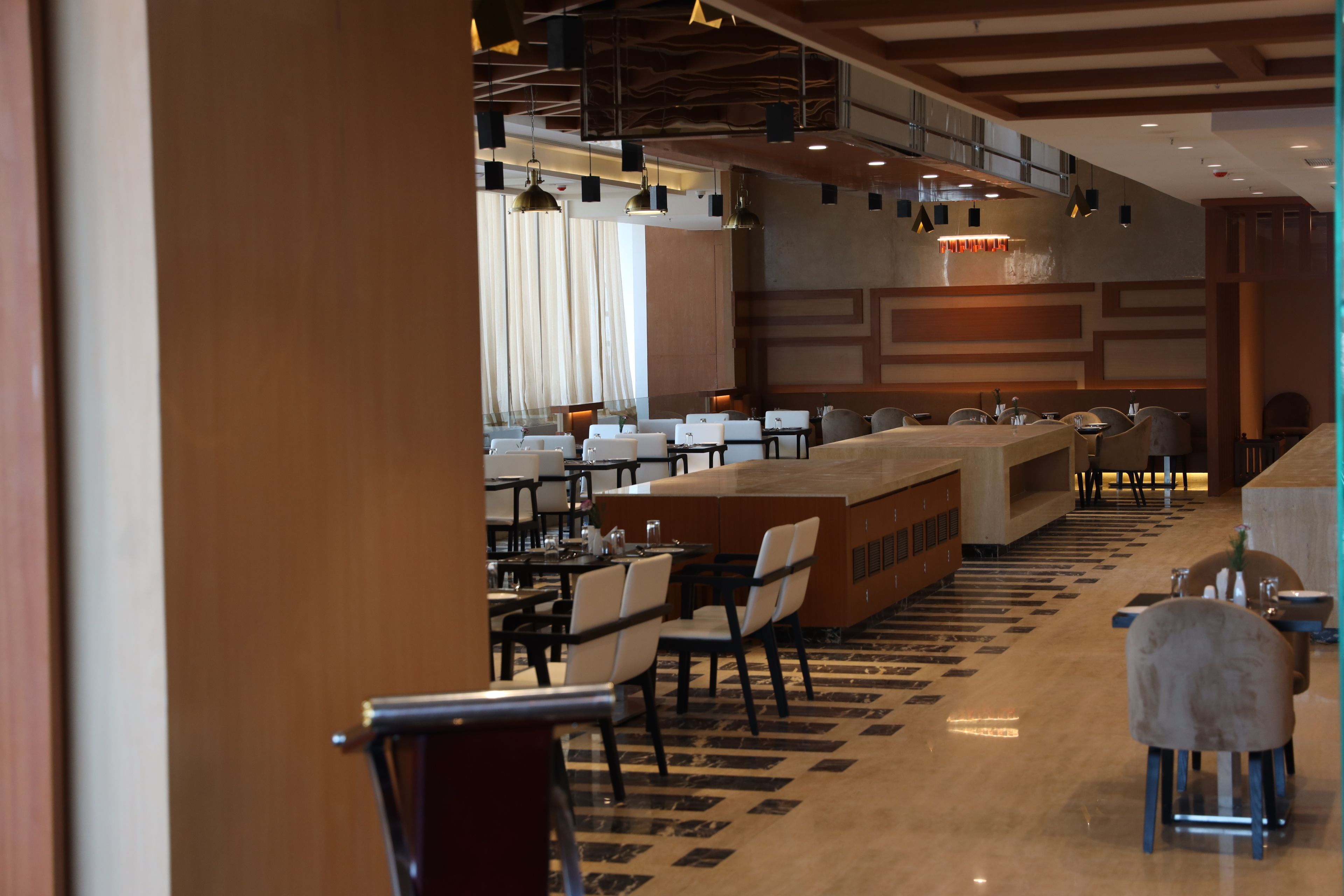 Um hall de hotel moderno com área de bar central, vários arranjos de assento e piso estampado.