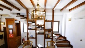 Quarto com escada de madeira, uma estante central em madeira e duas cadeiras.
