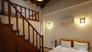 Quarto com escada de madeira, cama com roupa de cama branca e iluminação embutida na parede.