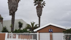 Uma entrada fechada com palmeiras, um edifício com a placa