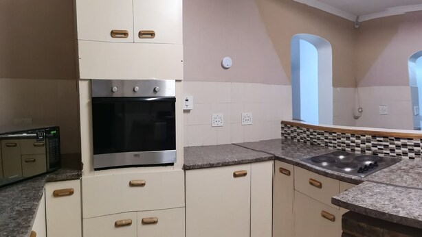 Uma cozinha compacta com fogão, micro-ondas e pia.