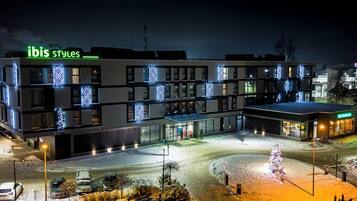 Um hotel moderno com uma placa indicando "ibis styles" e uma área de estacionamento coberta de neve.