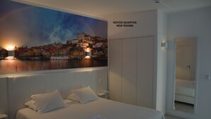 Quarto de hotel com cama, mesa de cabeceira, telefone na parede e espelho.