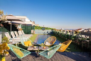 Área de piscina no terraço com espreguiçadeiras, uma piscina pequena e um bar.