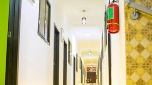 Corredor de hotel com extintor preso na parede, corrimão e parede estampada à direita.