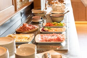 Buffet com diversos itens, incluindo carnes, queijos e saladas.