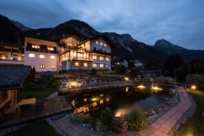 Um hotel com um prédio grande, um lago e montanhas ao fundo.
