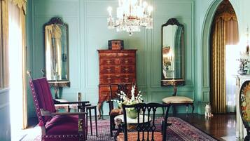 Quarto com lustre, aparador de madeira, espelho e cadeira vermelha.