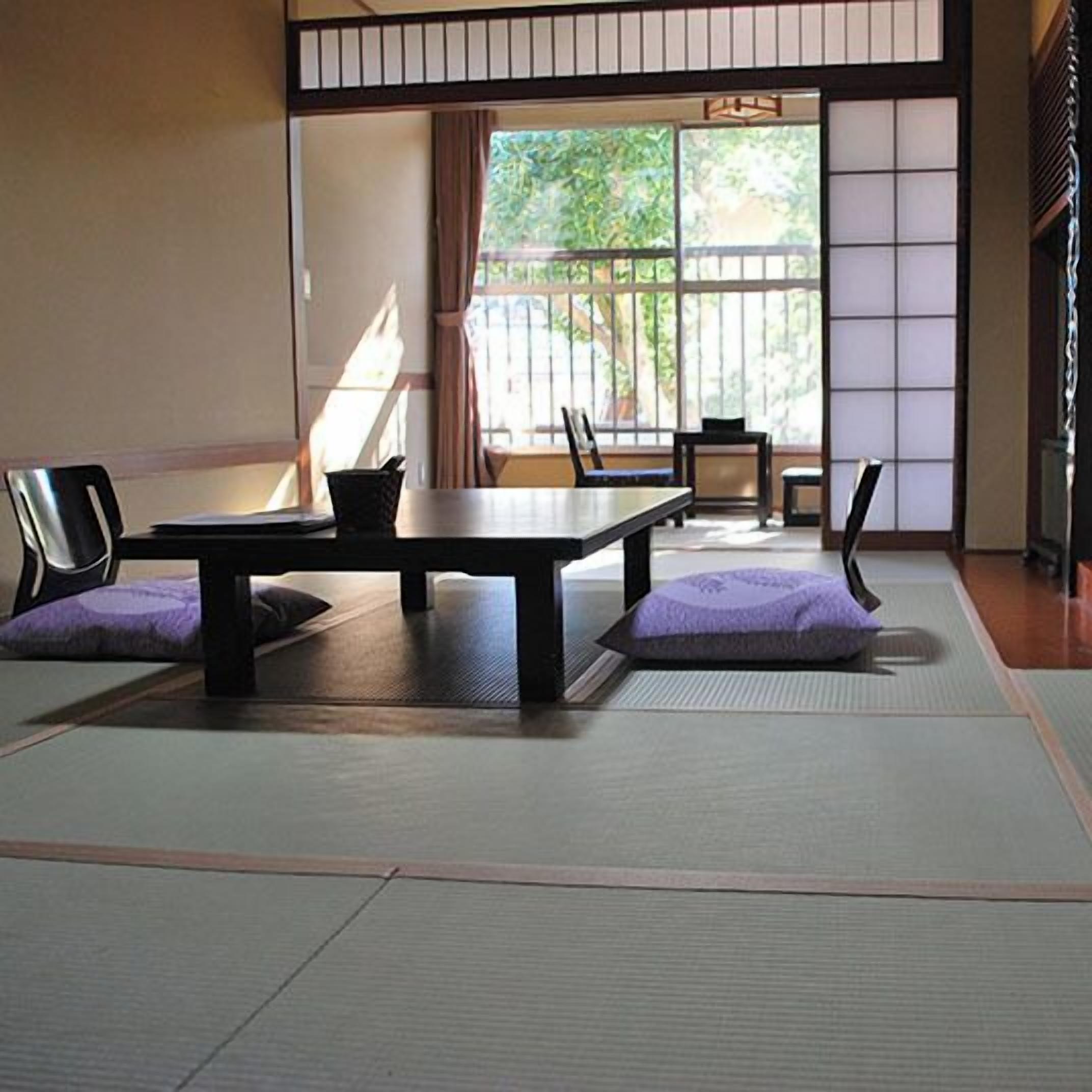 Um quarto japonês tradicional com tatames, uma mesa baixa e almofadas.