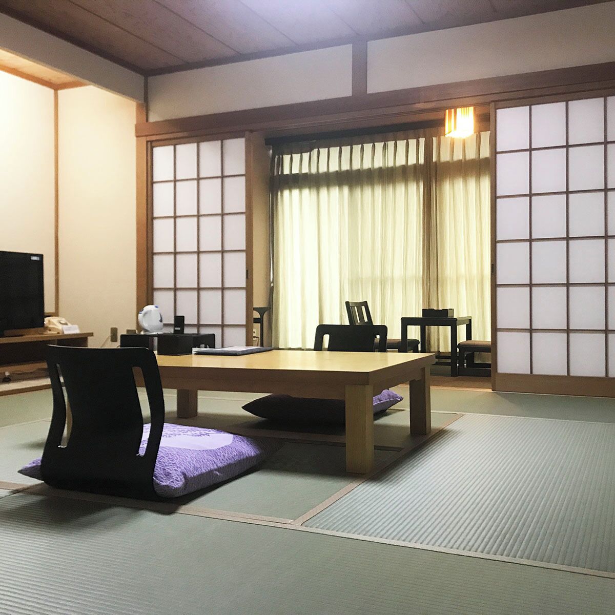 Um quarto japonês tradicional com tatames, uma mesa baixa e cadeiras.