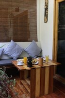 Uma mesa de madeira com itens de café da manhã, um sofá com almofadas e um objeto decorativo na parede.