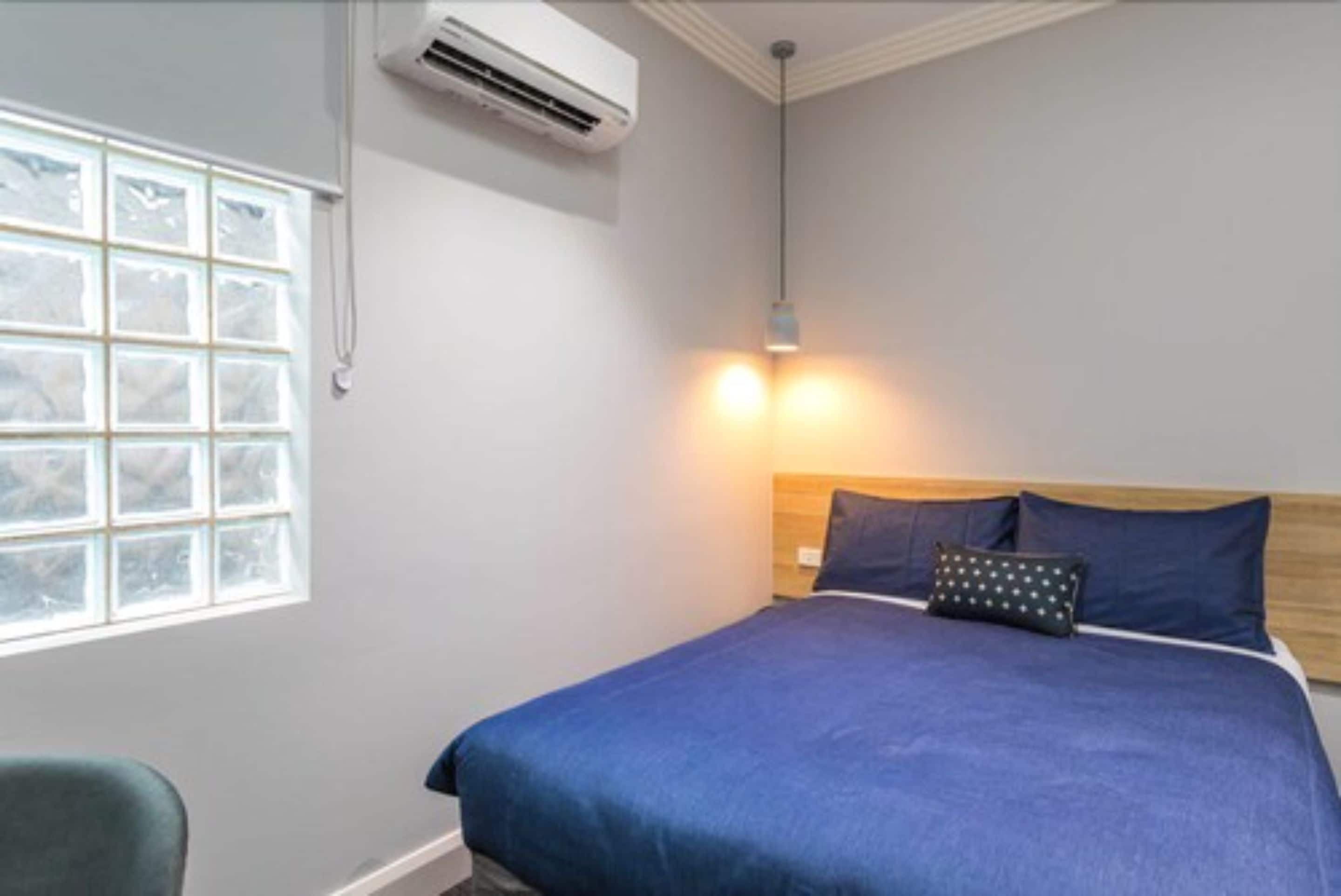 Quarto com cama, janela e ar condicionado.