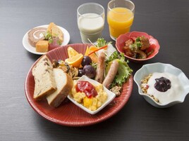 Prato de café da manhã com torradas, ovos mexidos, linguiça e uma tigela de iogurte com frutas vermelhas.