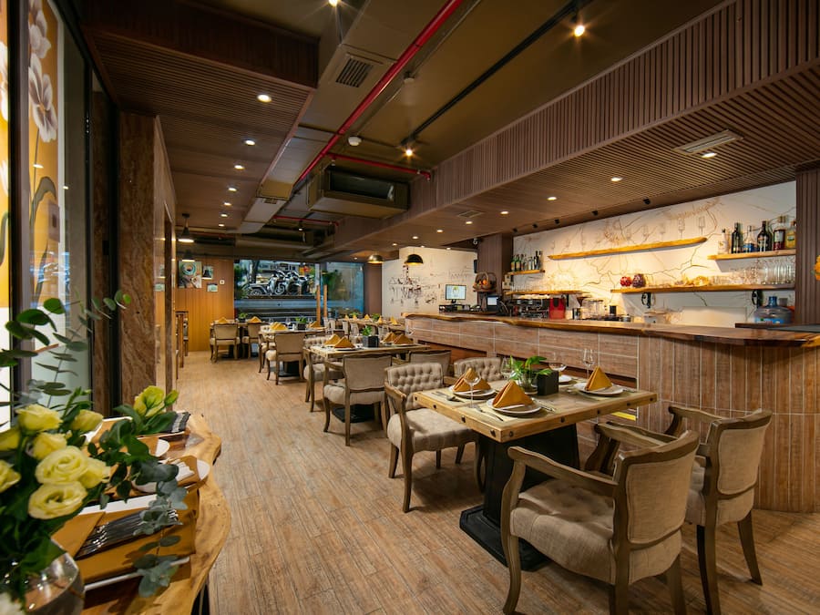 Restaurante com móveis de madeira, área de bar e vista para a rua.