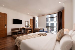 Quarto de hotel com uma cama, uma escrivaninha com computador, televisão e varanda com vista.
