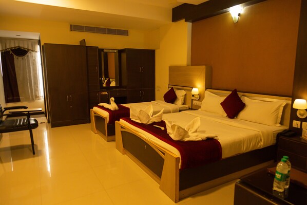 Quarto de hotel com duas camas, uma escrivaninha, uma cadeira, um guarda-roupa e uma casa de banho.