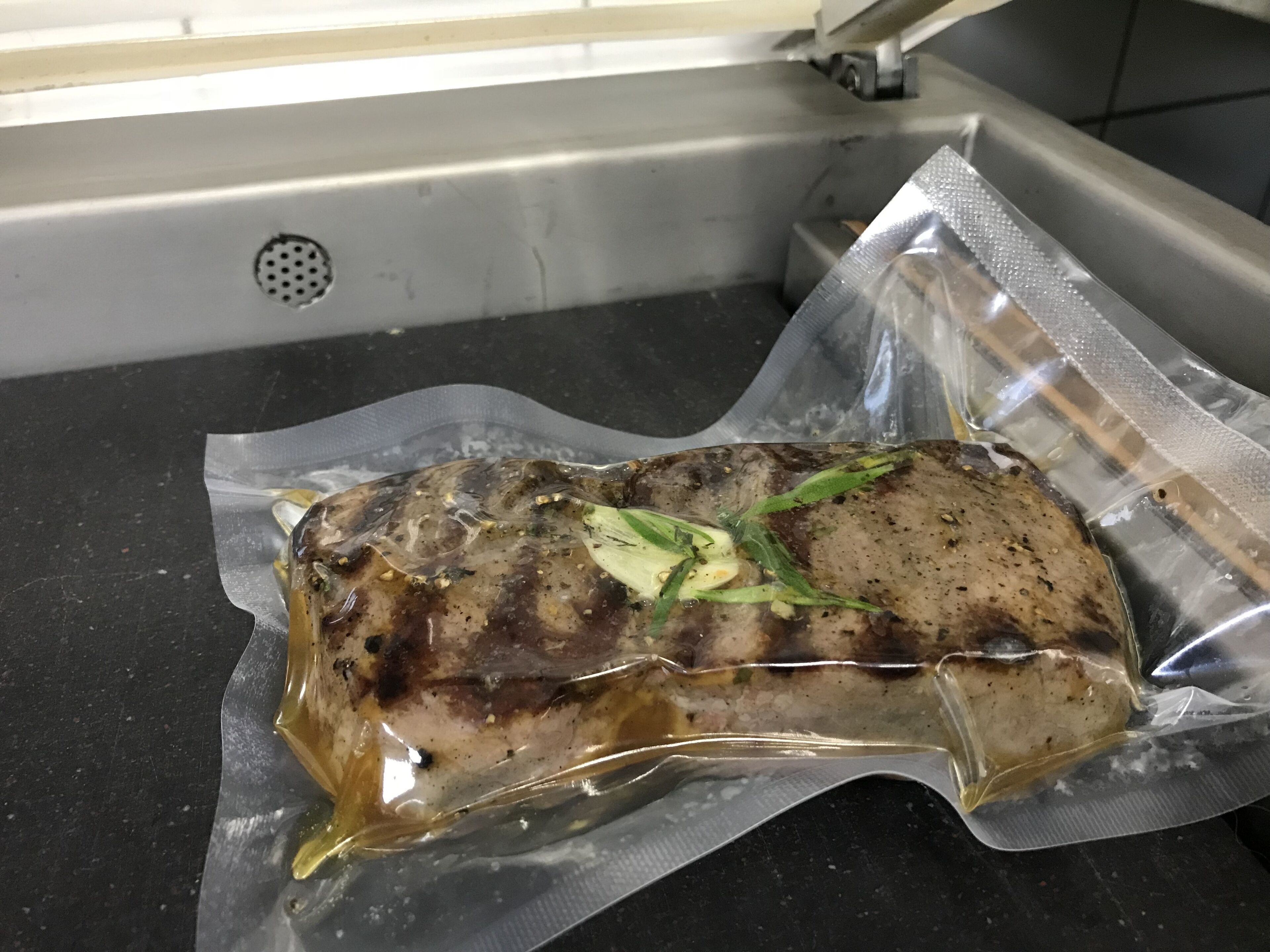 Bife dentro de um saco plástico sobre bancada de cozinha.