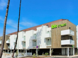 Um edifício moderno de hotel com uma placa indicando 'ibis styles' e uma placa de 'proibido estacionar'.