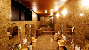 Casa de banho moderna com paredes de granito, teto de madeira e várias lavatórios com espelhos.