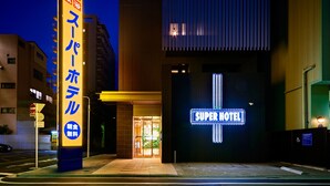 Entrada de um hotel com um letreiro de neon que diz "SUPER HOTEL" e uma placa vertical com texto em japonês.