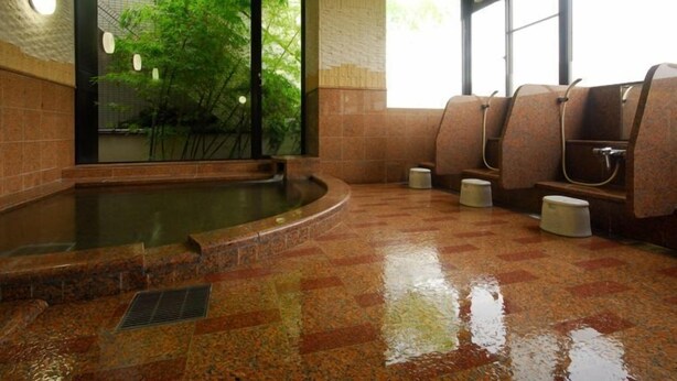 Uma sauna com chão molhado, bancos e uma janela com vista para árvores.