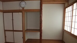 Um quarto japonês tradicional com tatames, uma mesa baixa com uma chaleira e uma tigela de fruta, e portas deslizantes.
