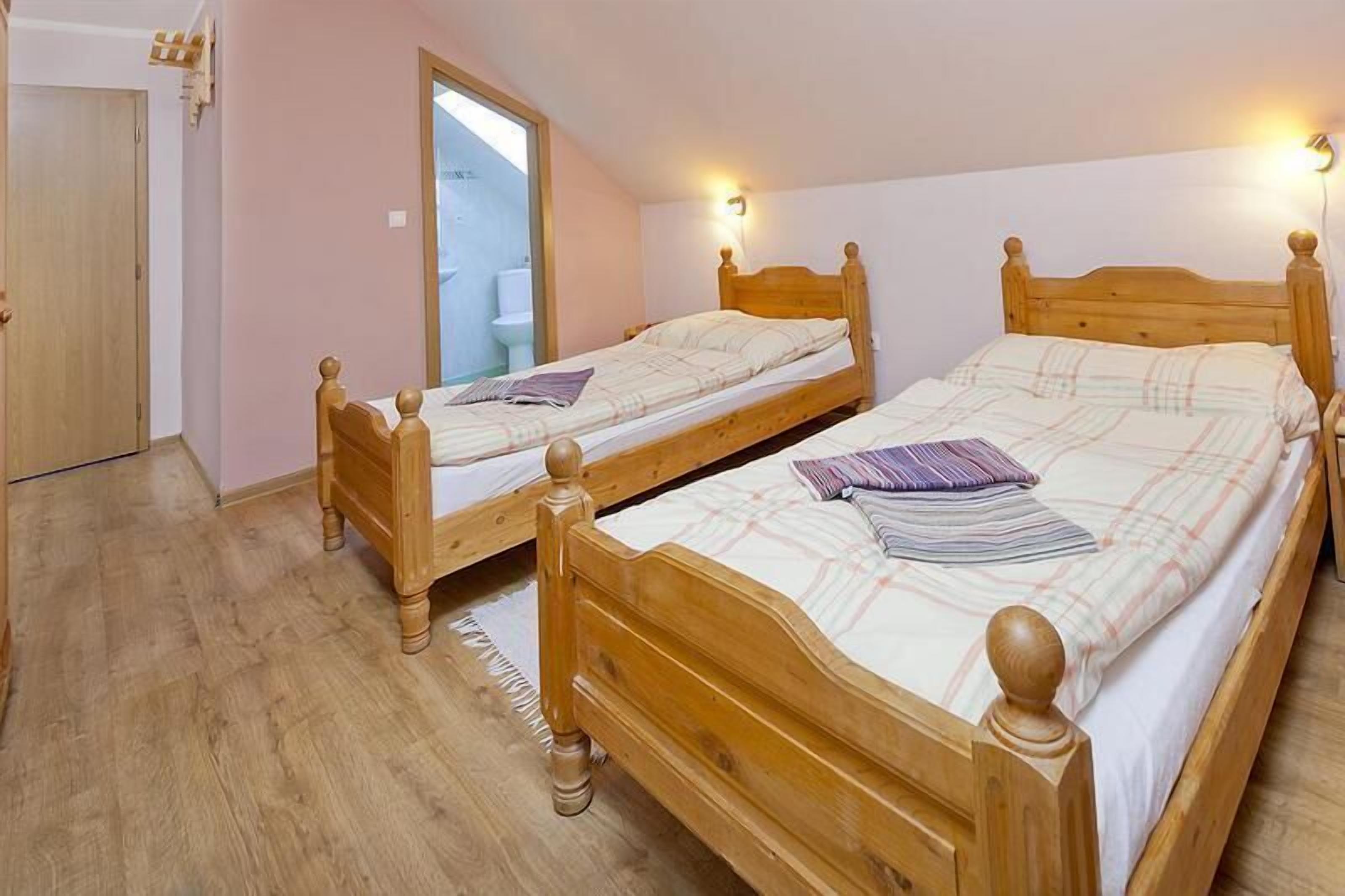 Quarto com duas camas de madeira, um guarda-roupa de madeira e um espelho.