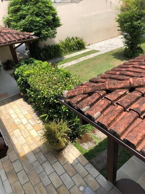 Um terraço no telhado com telhas, um caminho de pedra e vegetação bem cuidada.