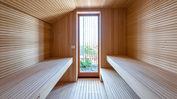 Uma sala de sauna com ripas de madeira nas paredes e bancos.
