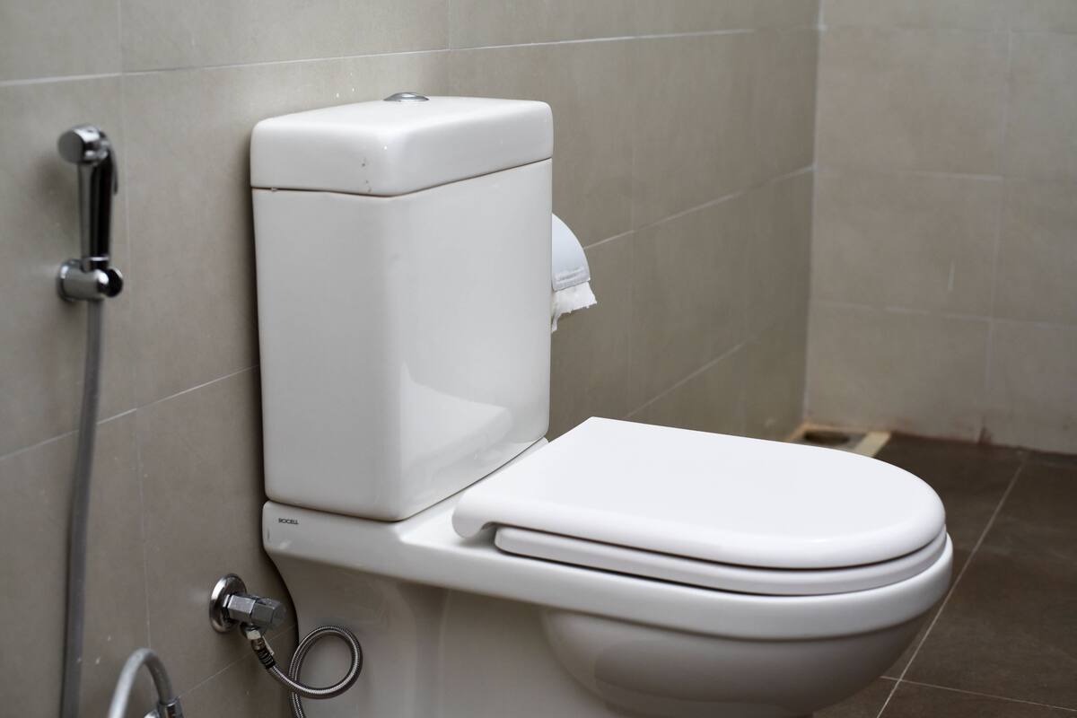 Uma casa de banho moderna com bidé, suporte de papel higiénico e rolo de papel higiénico à vista.