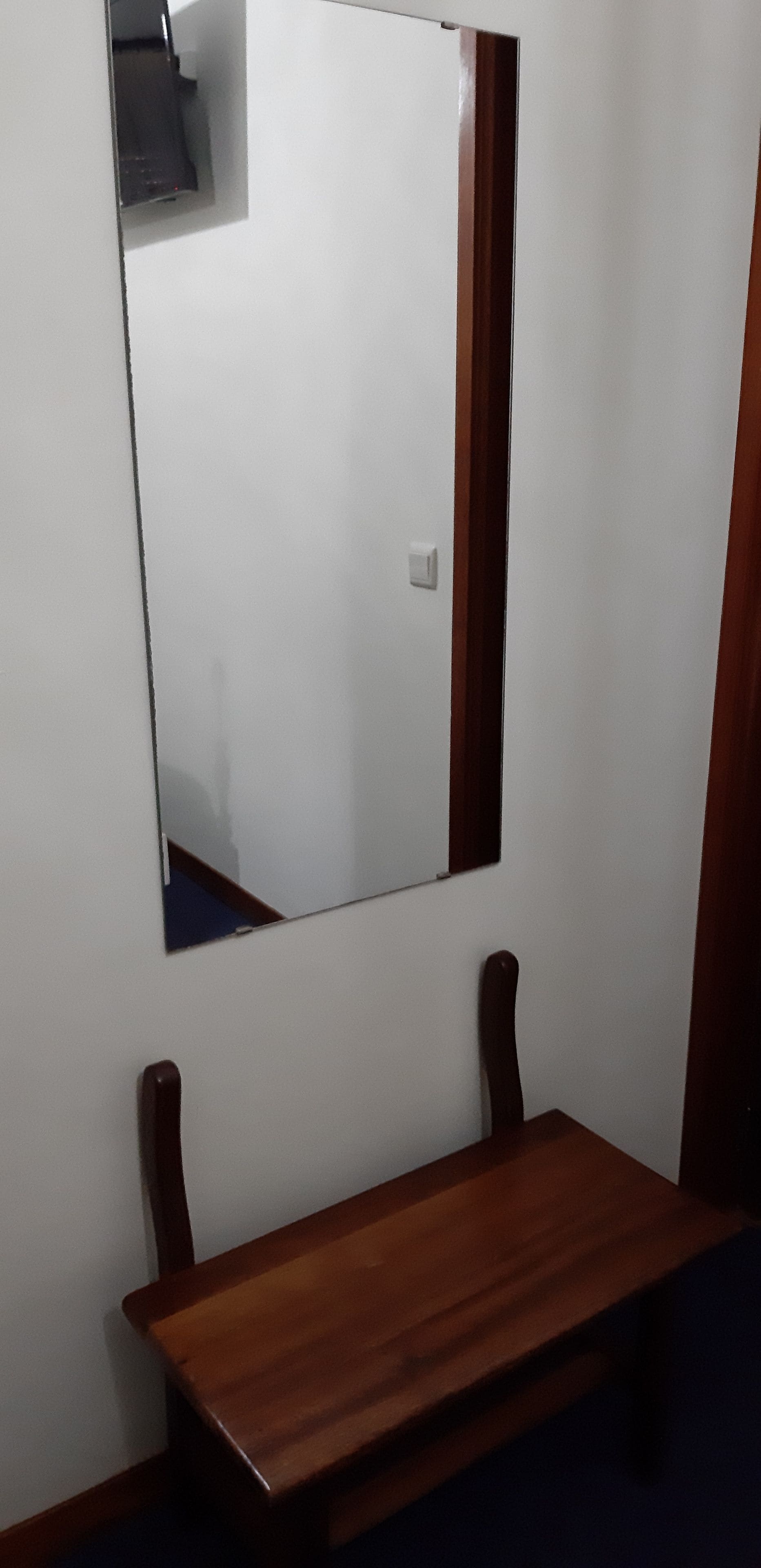 Quarto com uma mesa de madeira e um espelho grande na parede.