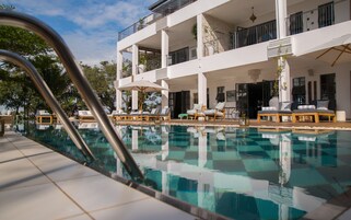 Um hotel moderno com piscina, área externa para sentar e estrutura em vários andares.